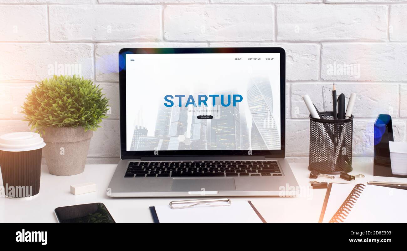 Modern laptop with ad of STARTUP platform website on office desk ...