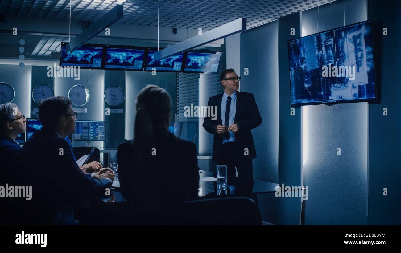 Chief of Operations Shows Surveillance Footage on Wall TV Screen to a ...