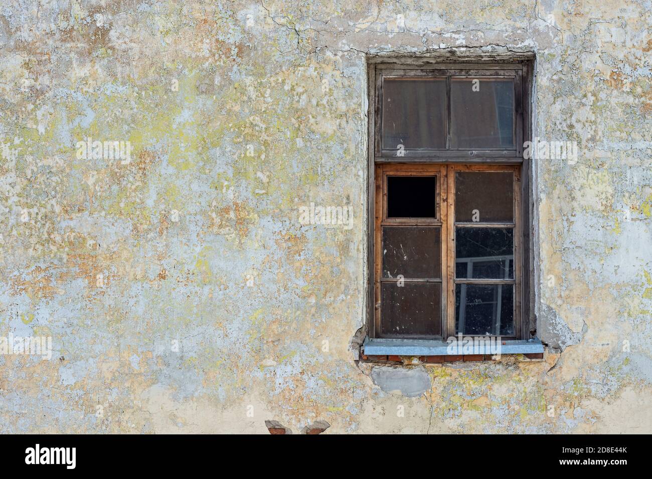 Old broken dirty window on an old wall with cracked plaster and peeling ...