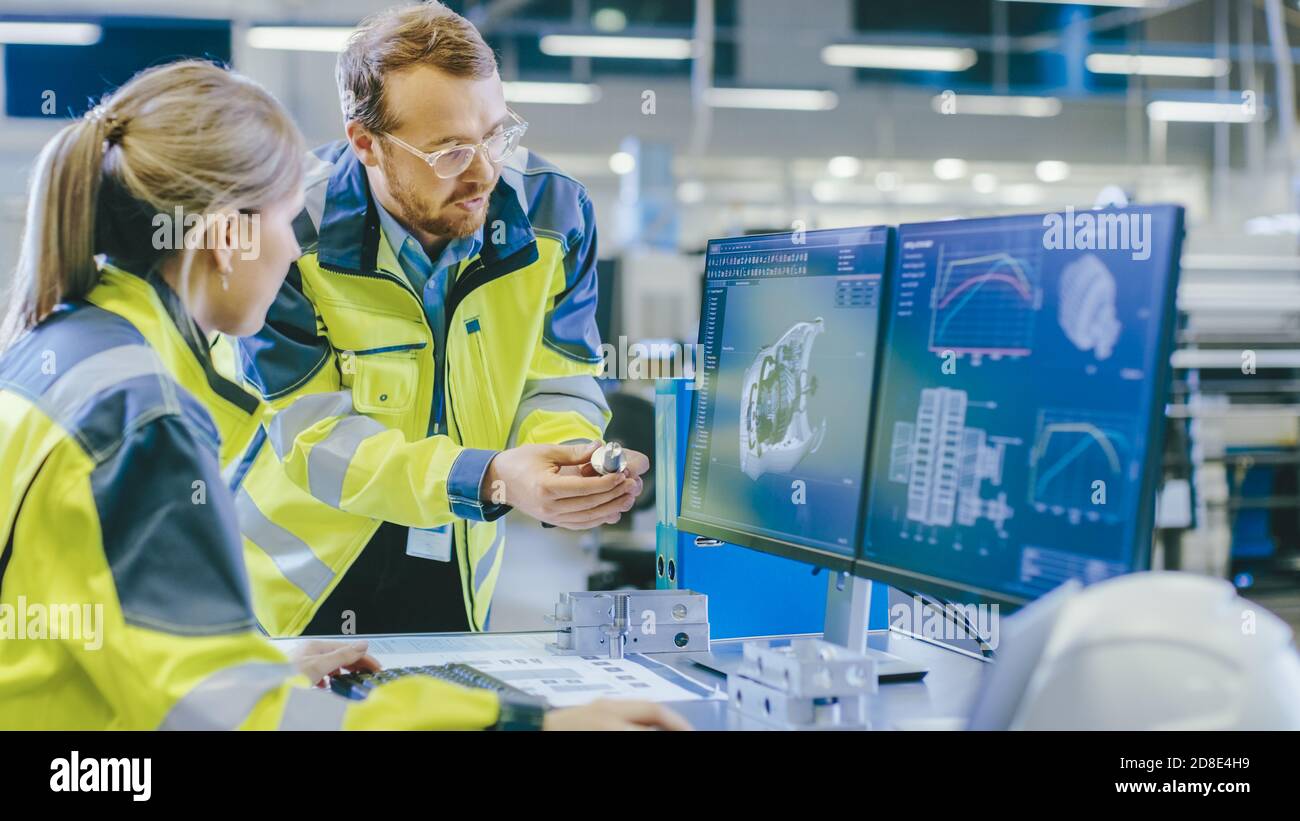 At the Factory: Male Mechanical Engineer Holds Component and Female ...