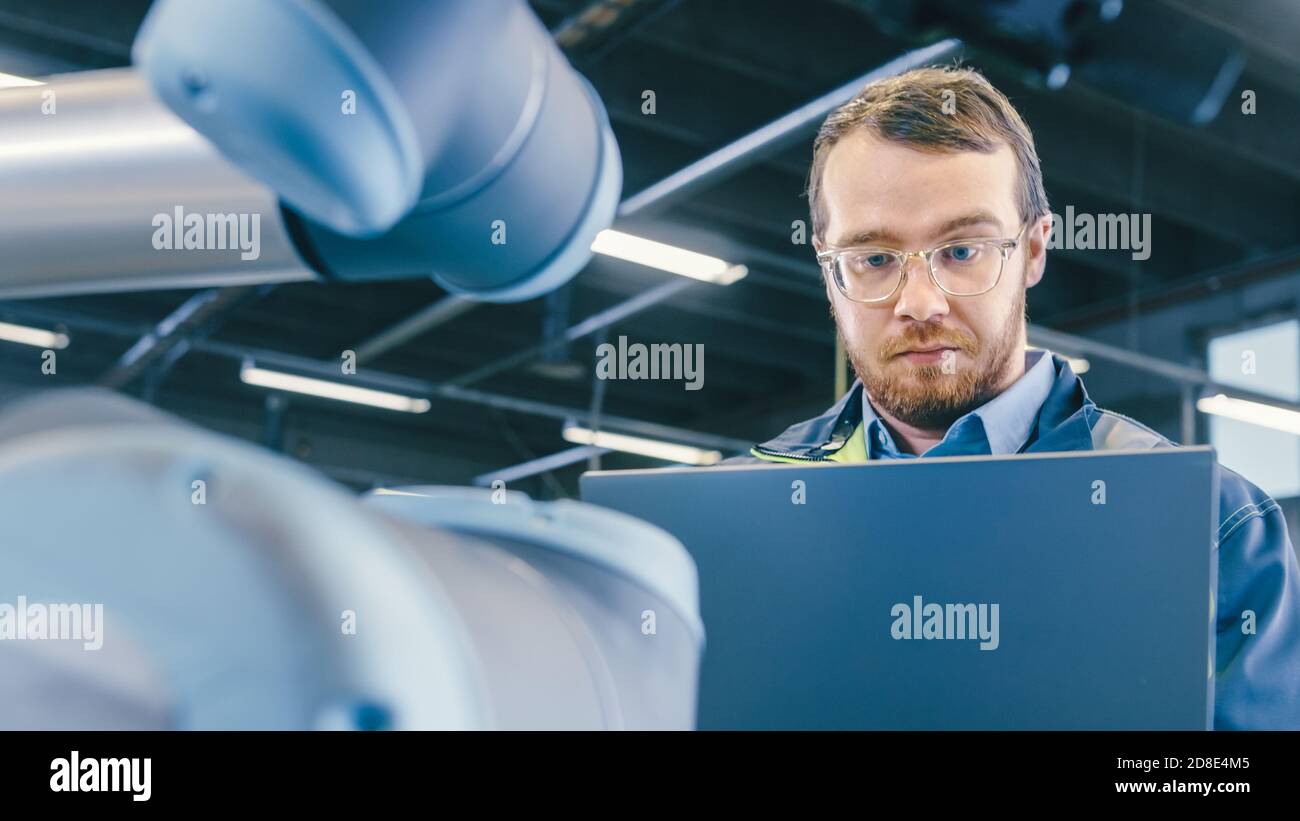 Low Angle Shot At the Factory: Automation Engineer Uses Laptop for ...