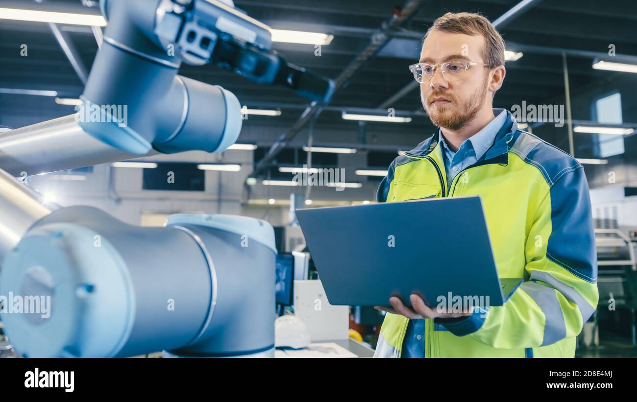 Low Angle Shot At the Factory: Automation Engineer Uses Laptop for ...