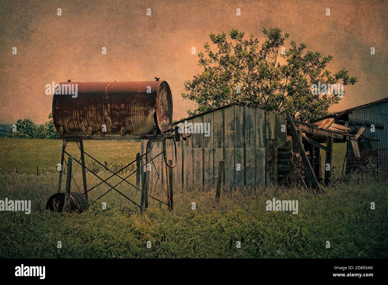 Metal fuel tank elevated on stilts next to abandoned farm outbuildings ...