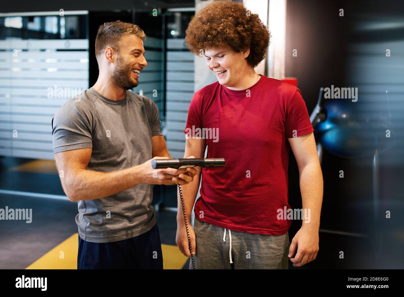 Overweight young man exercising gym with personal trainer Stock Photo ...