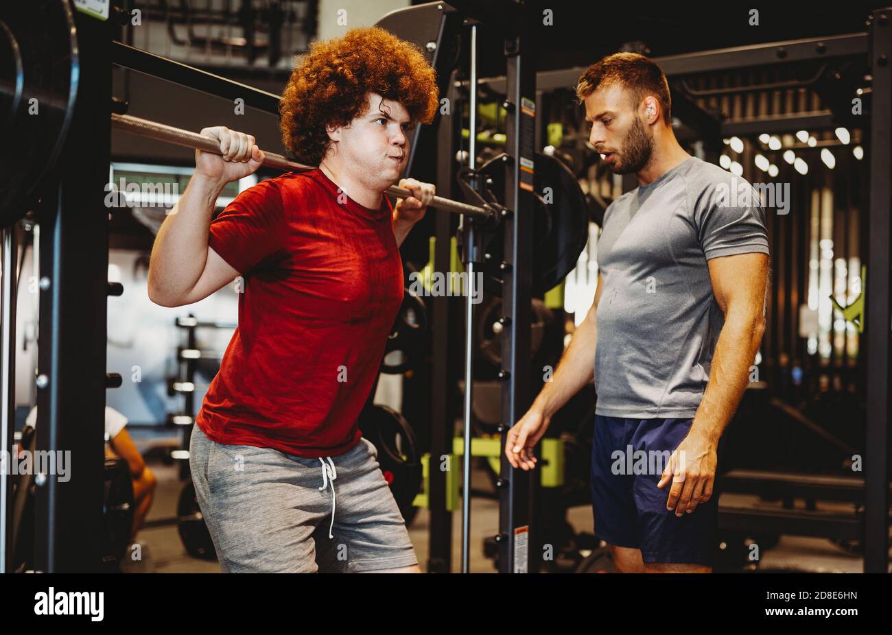 Overweight young man exercising gym with personal trainer Stock Photo ...