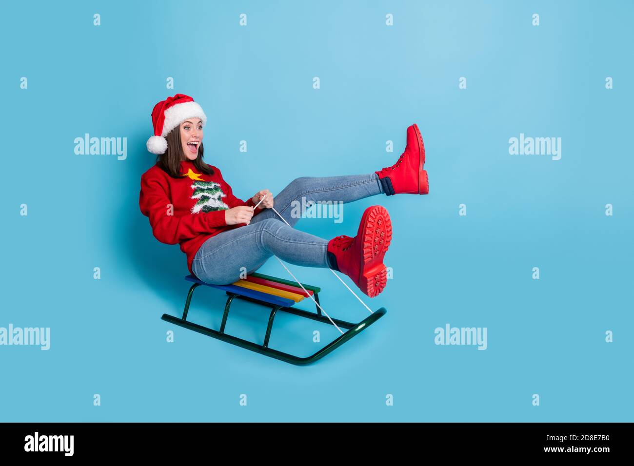 Photo portrait of woman riding sleigh with legs up screaming laughing ...