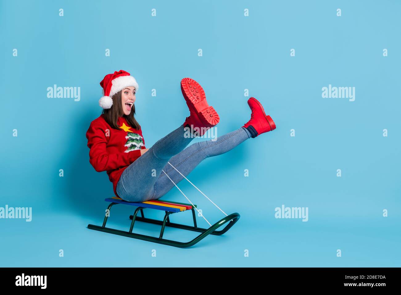 Photo portrait of young woman riding sled with legs up isolated on ...