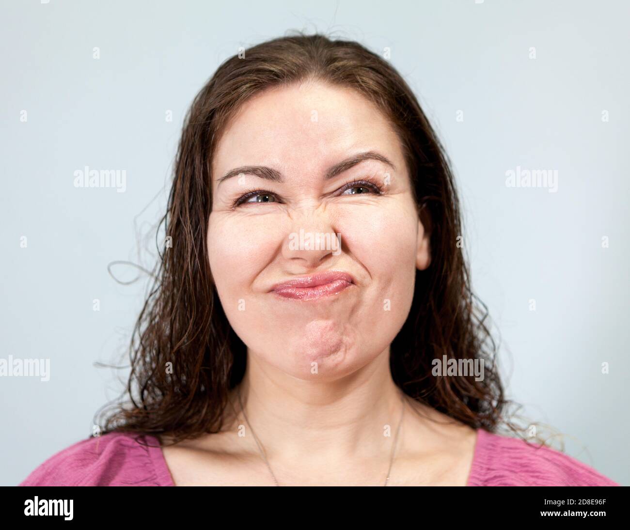 Dislike and discontent on the face of an adult woman, portrait on grey ...
