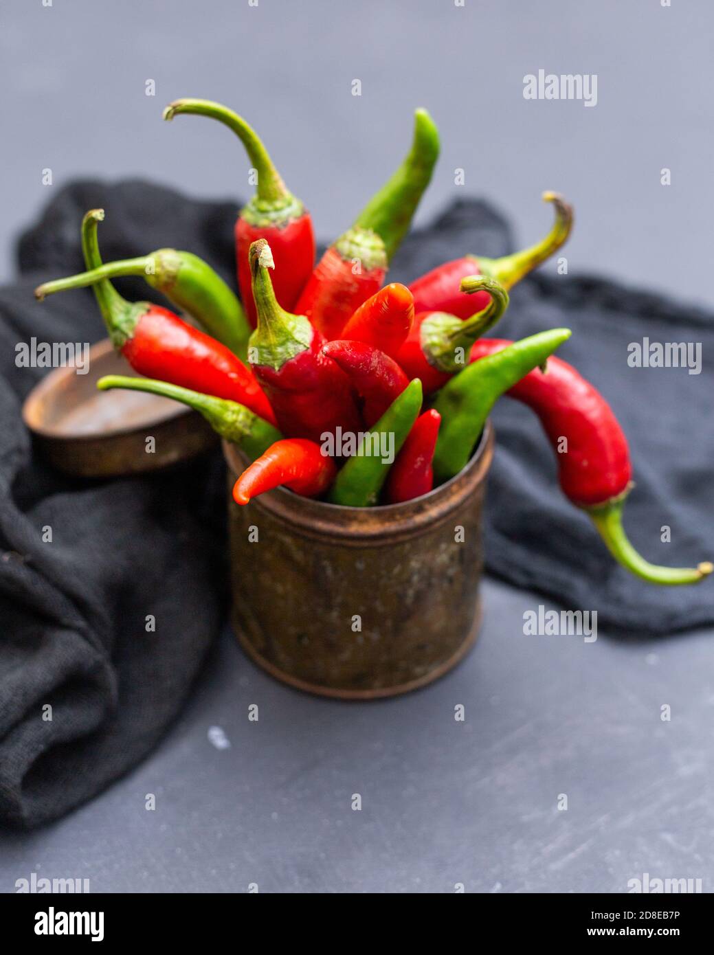 Vertical shot of the green and red hot chili peppers in a rusty cup ...