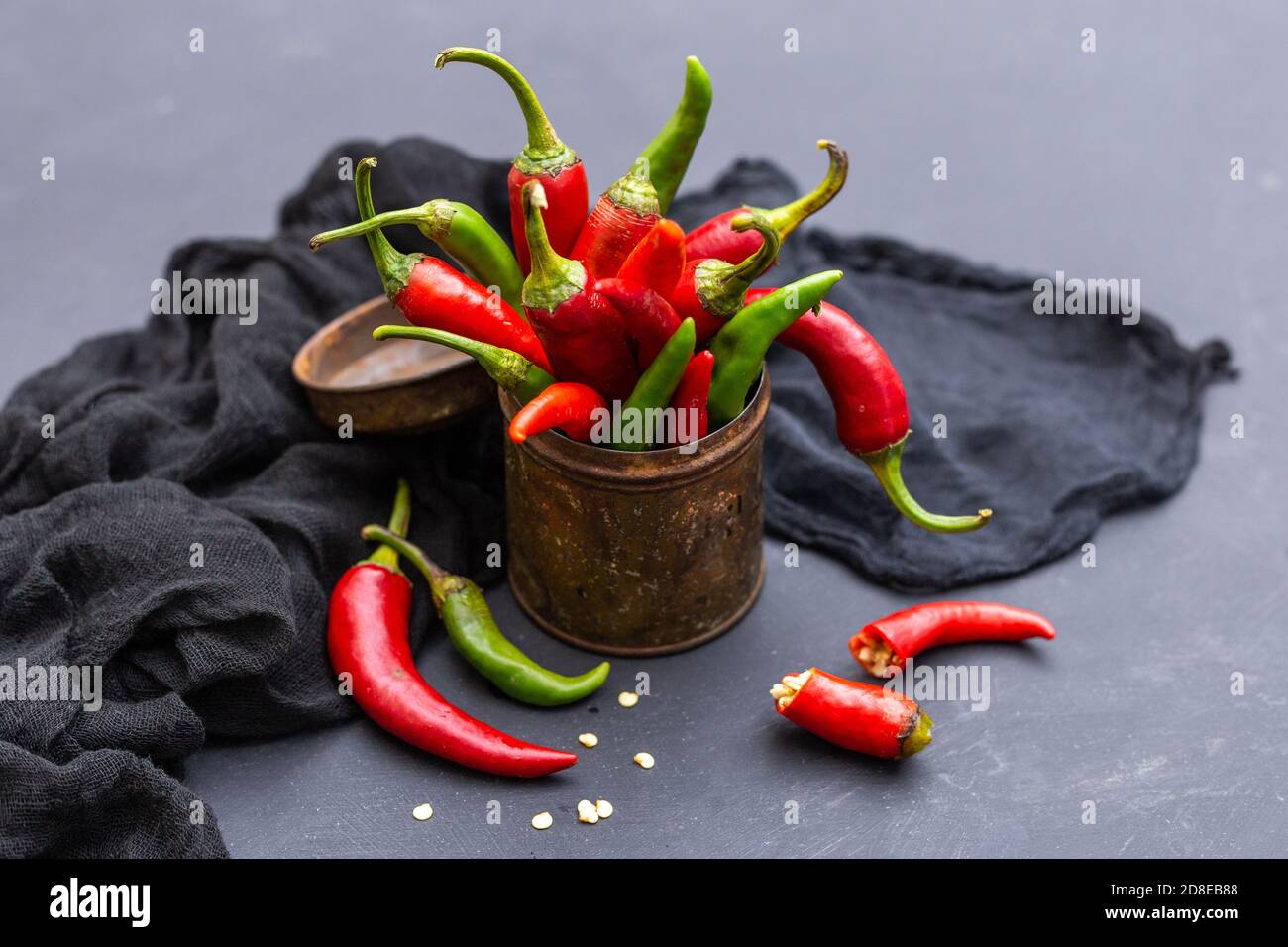 High angle shot of the green and red hot chili peppers in a rusty cup ...