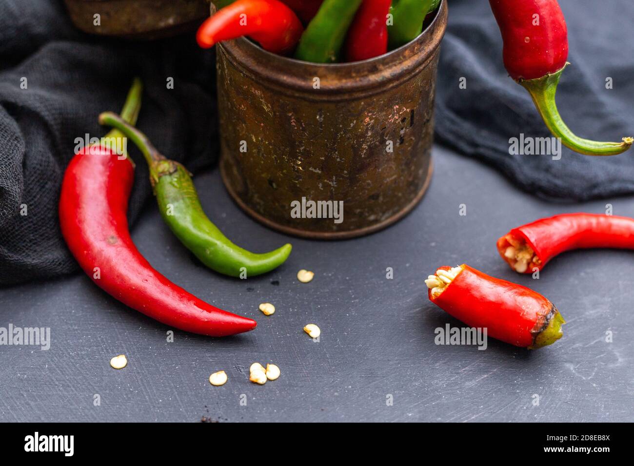 Top view of the green and red hot chili peppers in a rusty cup with ...