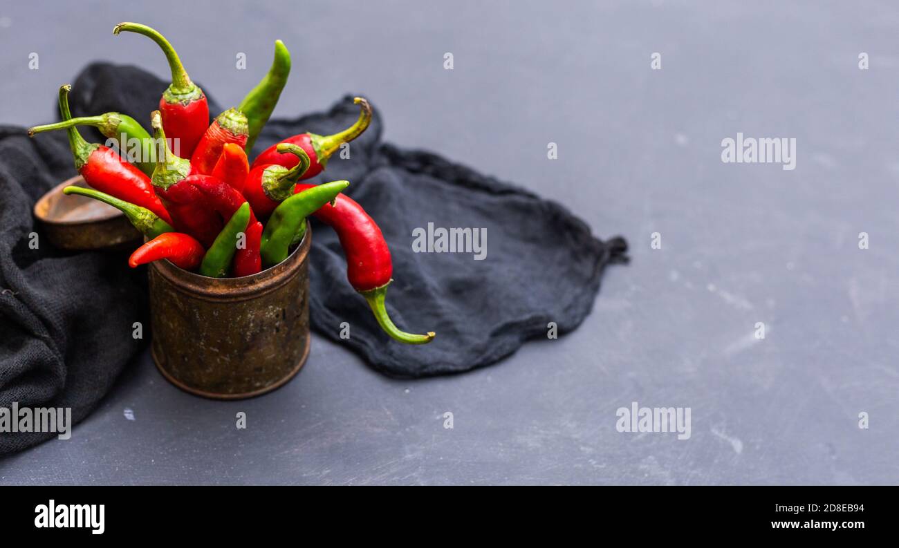 High angle shot of the green and red hot chili peppers in a rusty cup ...