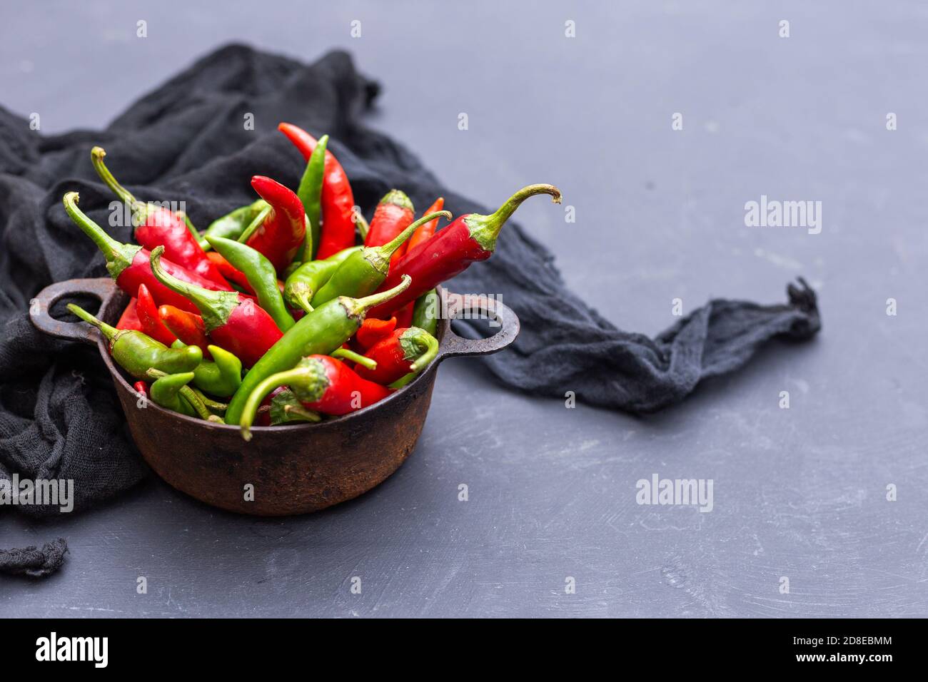 Top view of the green and red hot chili peppers in a rusty cup with ...
