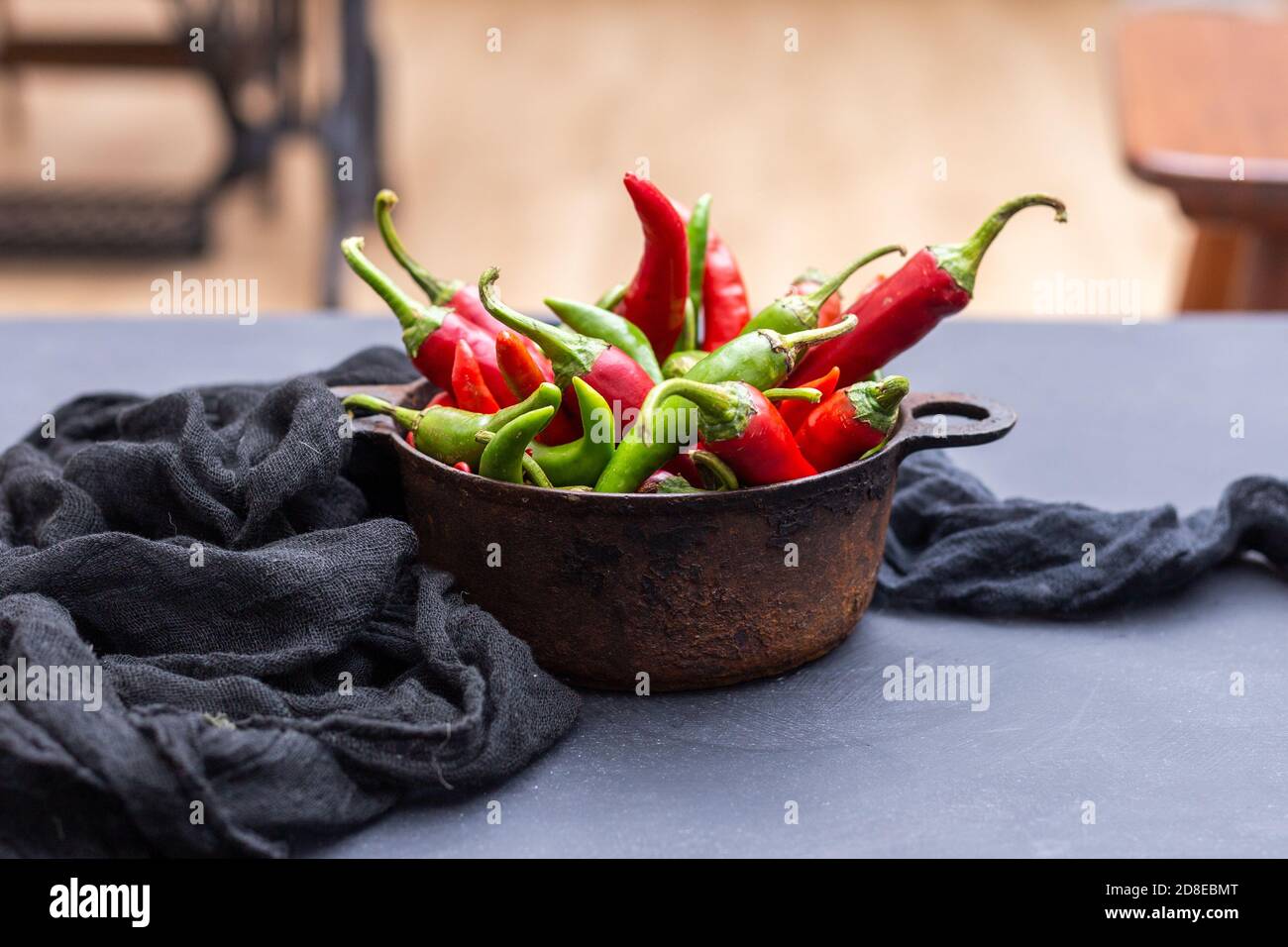 Top view of the green and red hot chili peppers in a rusty cup with ...