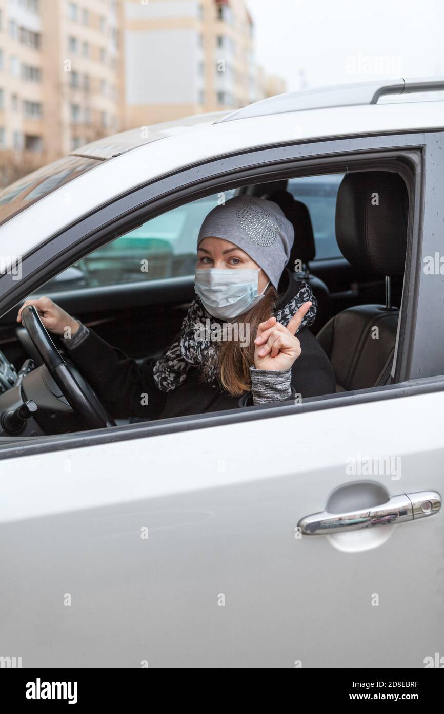 Female driver wearing face mask gesturing with forefinger during ...