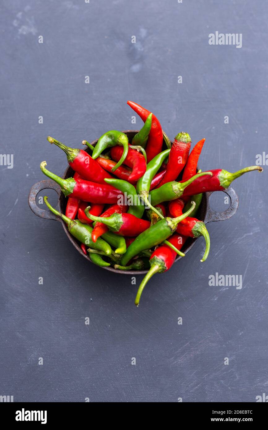 Vertical top view of the green and red hot chili peppers in a rusty cup ...