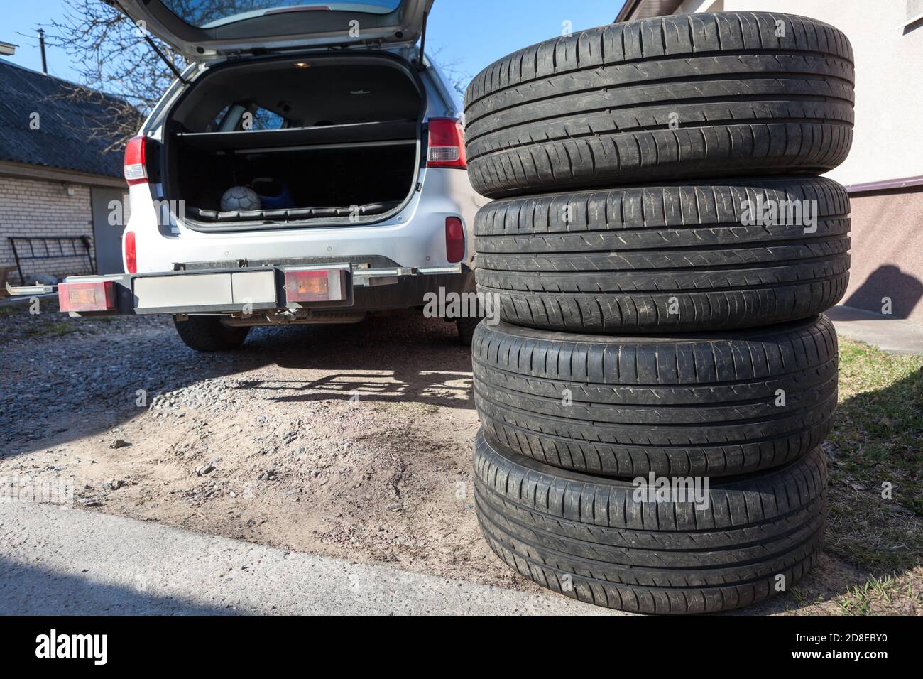 Four summer tyres lying on land next to opened trunk of suv car ...