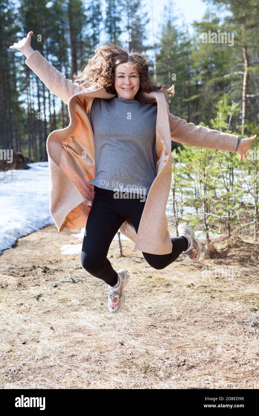 Happy Caucasian woman hopping in the park and celebrating. Caucasian ...