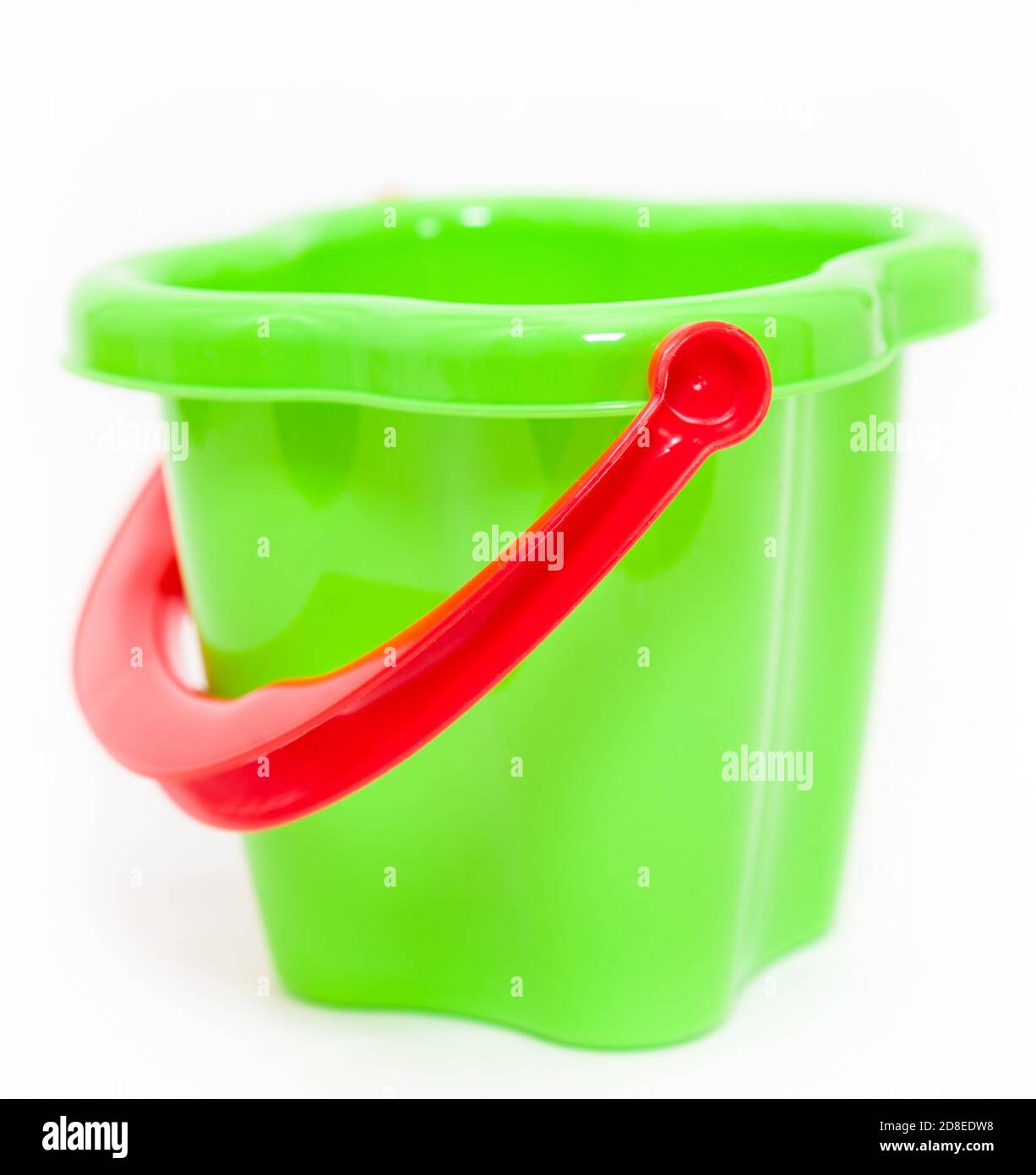 Green plastic children bucket with red handle on a white background ...