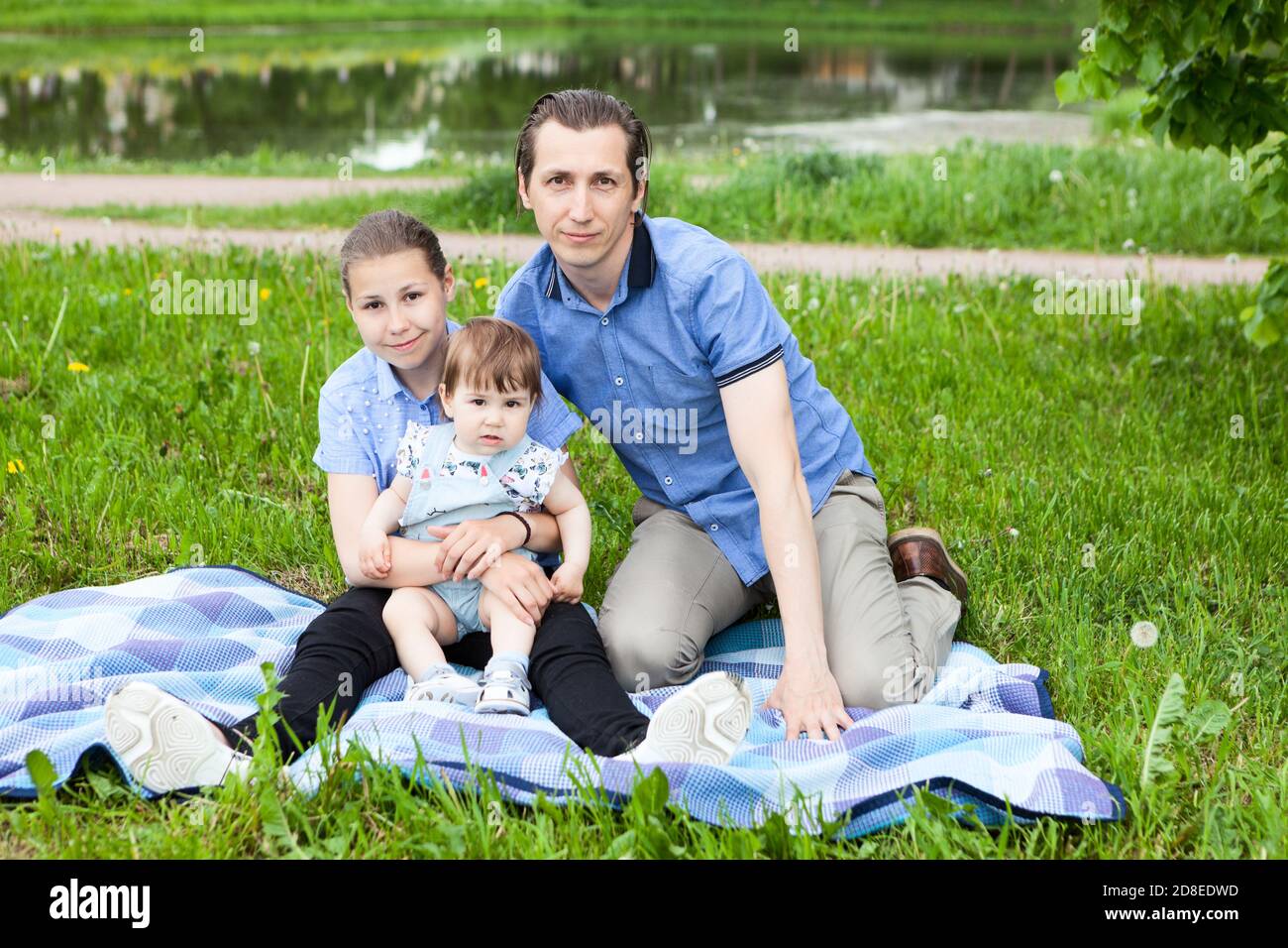 Single father and two daughters sitting on blanket on lawn in urban ...