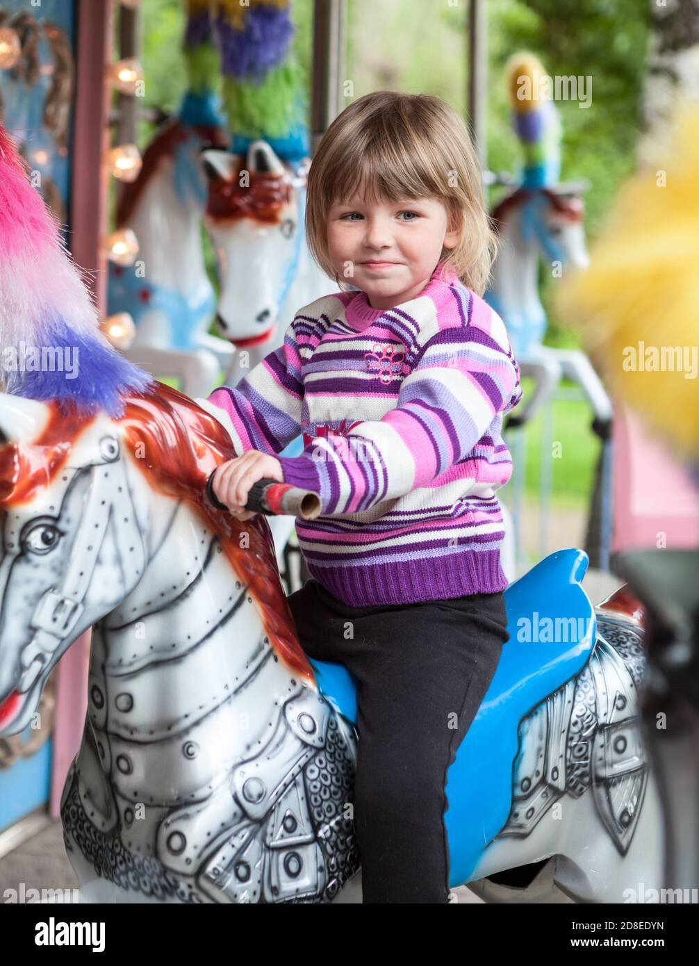 Adorable little kid girl riding on a merry-go-round carousel horse at ...