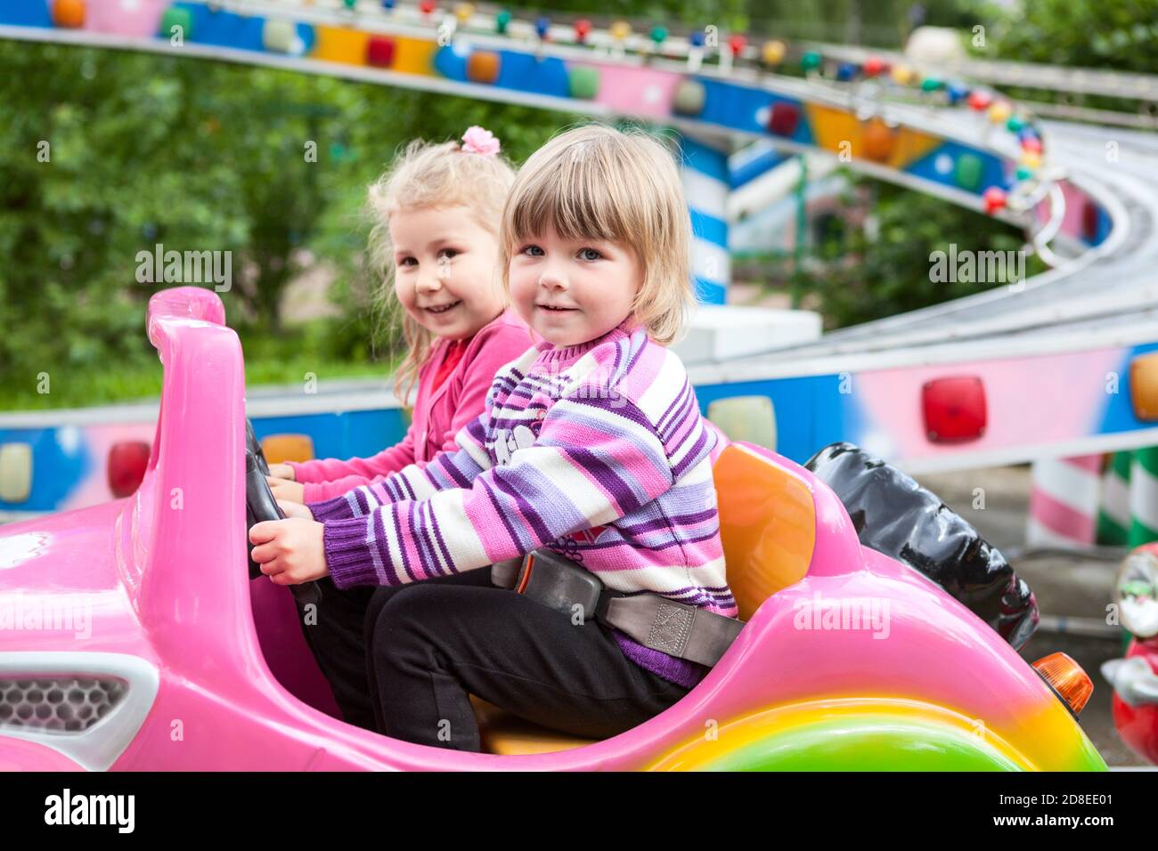 Two happy little girls having fun in summer amusement park with riding ...