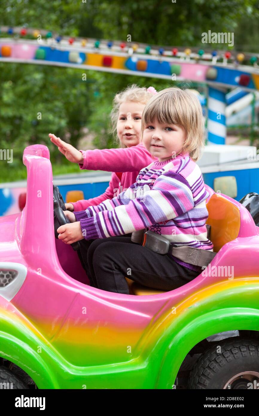 Two happy Caucasian little girls having fun in outdoor amusement park ...