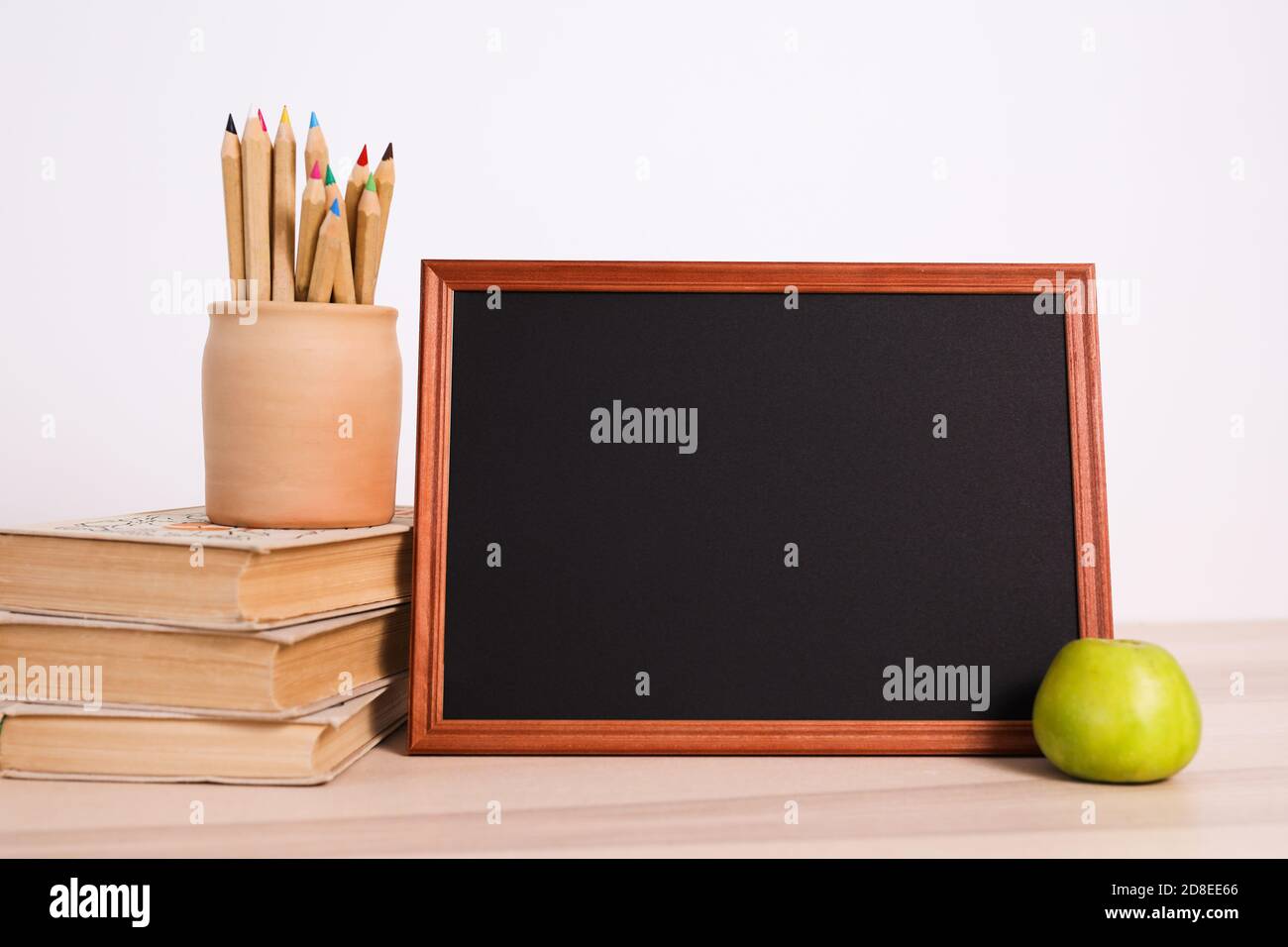 Chalk black board, apple and chalk, against background of books, copy ...