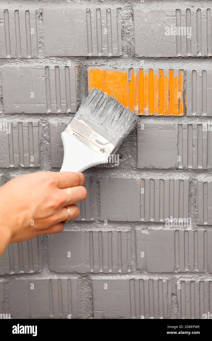 Human hand painting last orange brick of wall in grey color Stock Photo ...