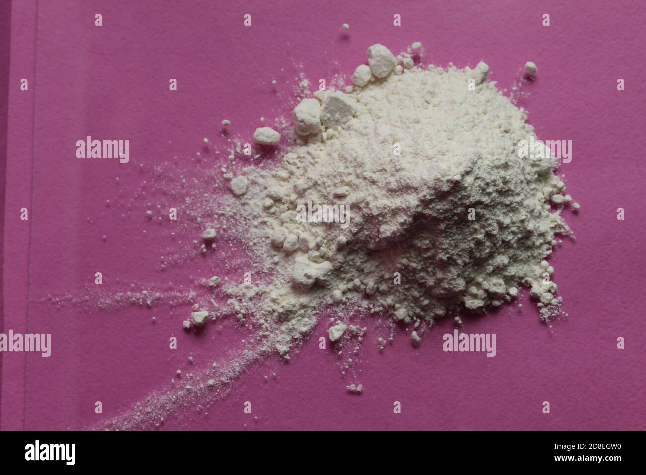 flour or powdered sugar is piled in a pile on a fuchsia pink background ...
