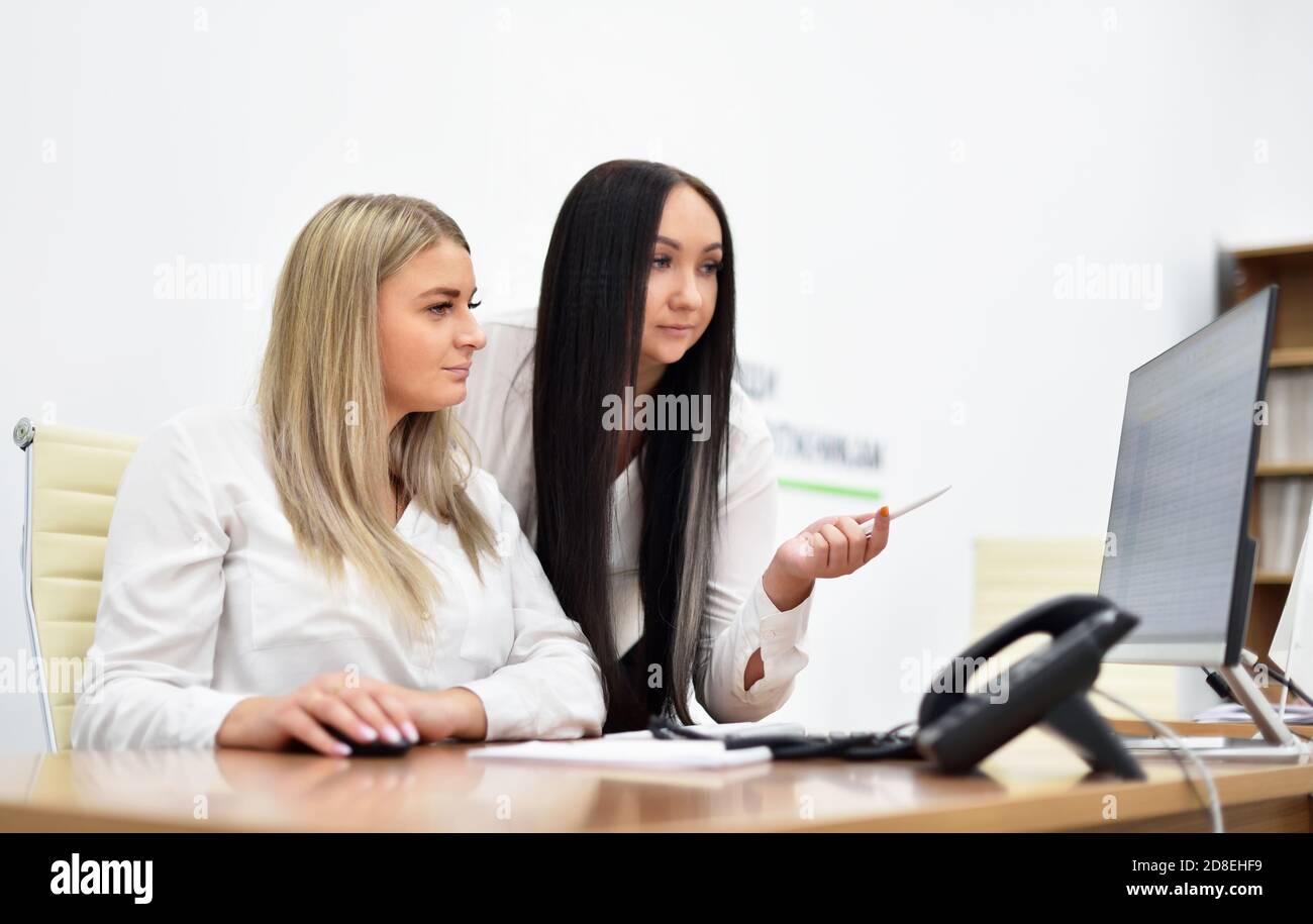 Two young women office workers are discussion and looking at the ...