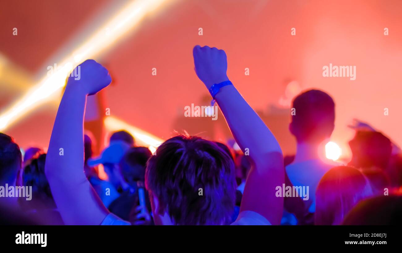 Teenage boy partying, cheering, raising hands up at rock concert in ...