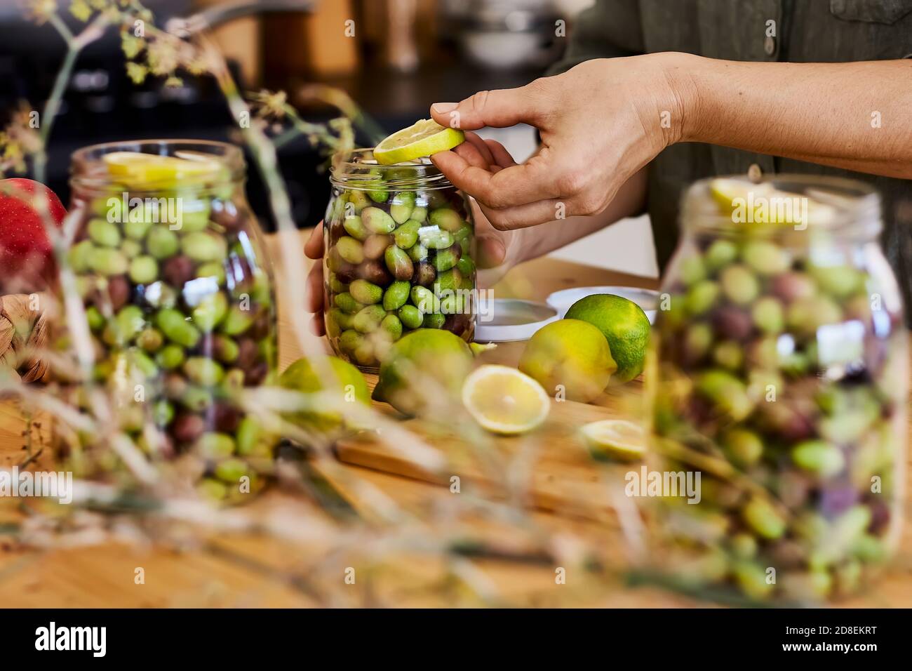 Woman prepares fermented olives in glass jars in the kitchen. Autumn ...