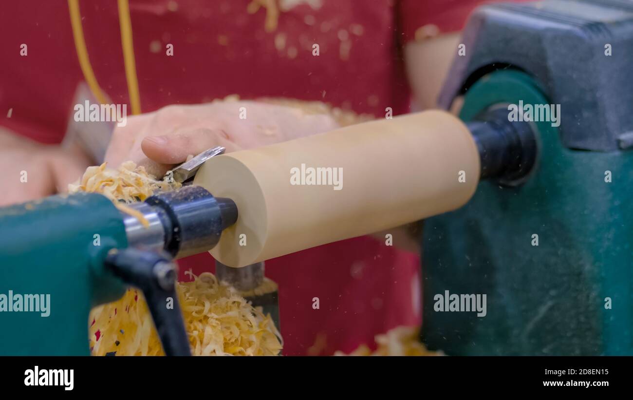 Professional man carpenter using skew chisel for shaping piece of wood ...