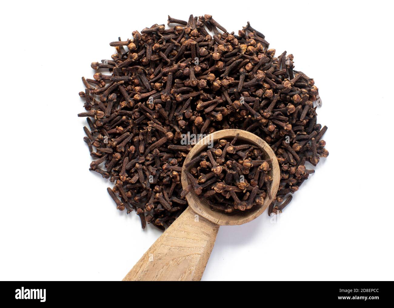 pile of whole cloves in a wooden spoon isolated on a white background ...