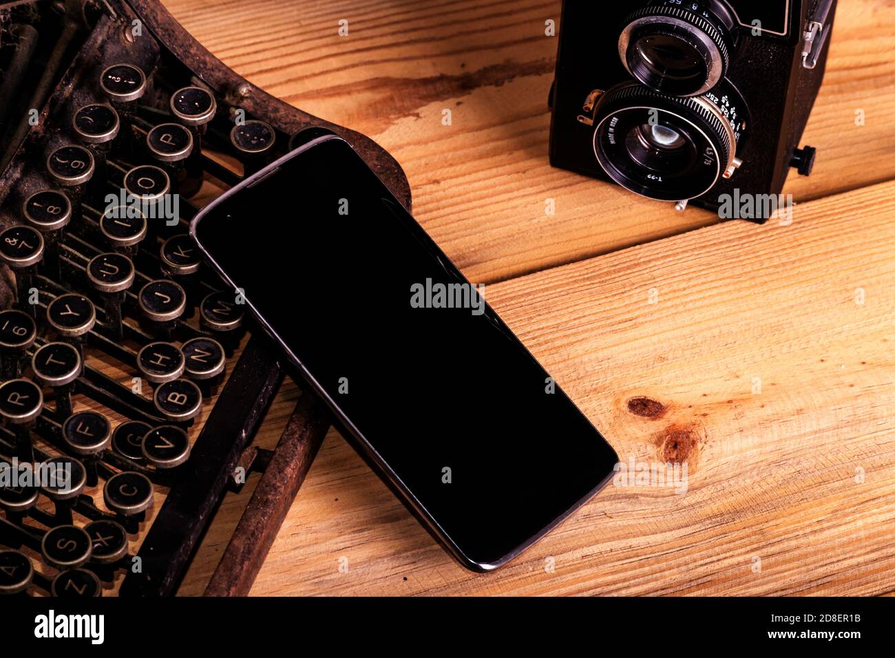 A mobile phone leaning upon an old broken typing machine with an ...