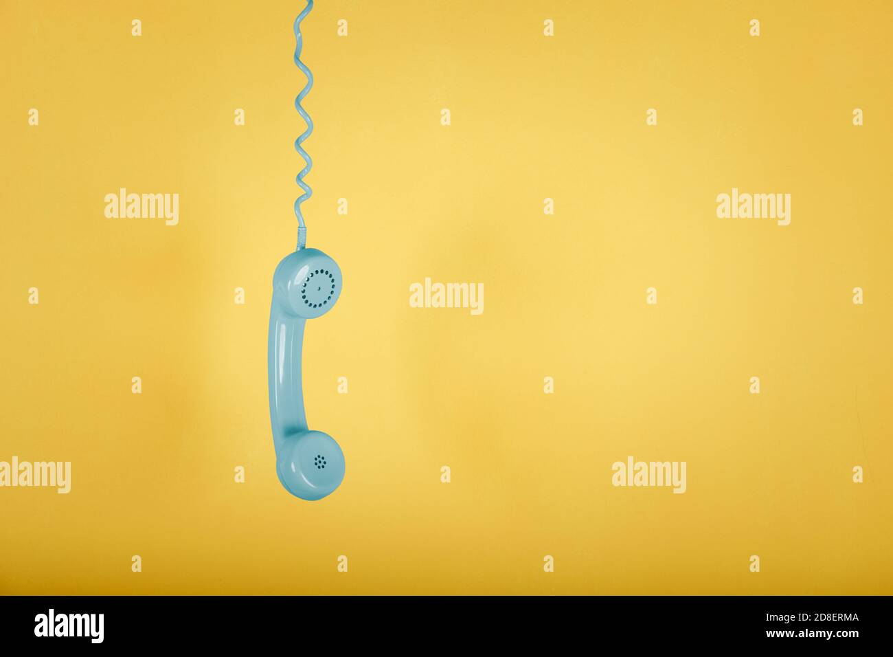 blue vintage telephone hanging on yellow background Stock Photo - Alamy