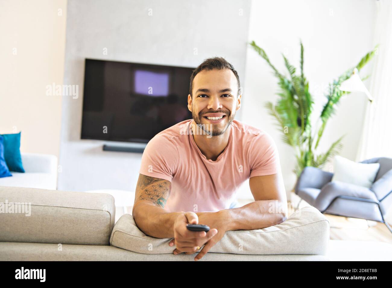Portrait of smiling man sitting on sofa and watching tv Stock Photo - Alamy