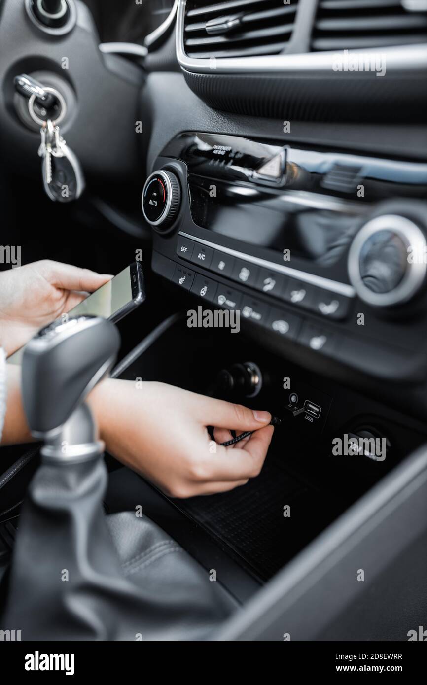 Interior view of a modern new car. Female model in the car charging her ...