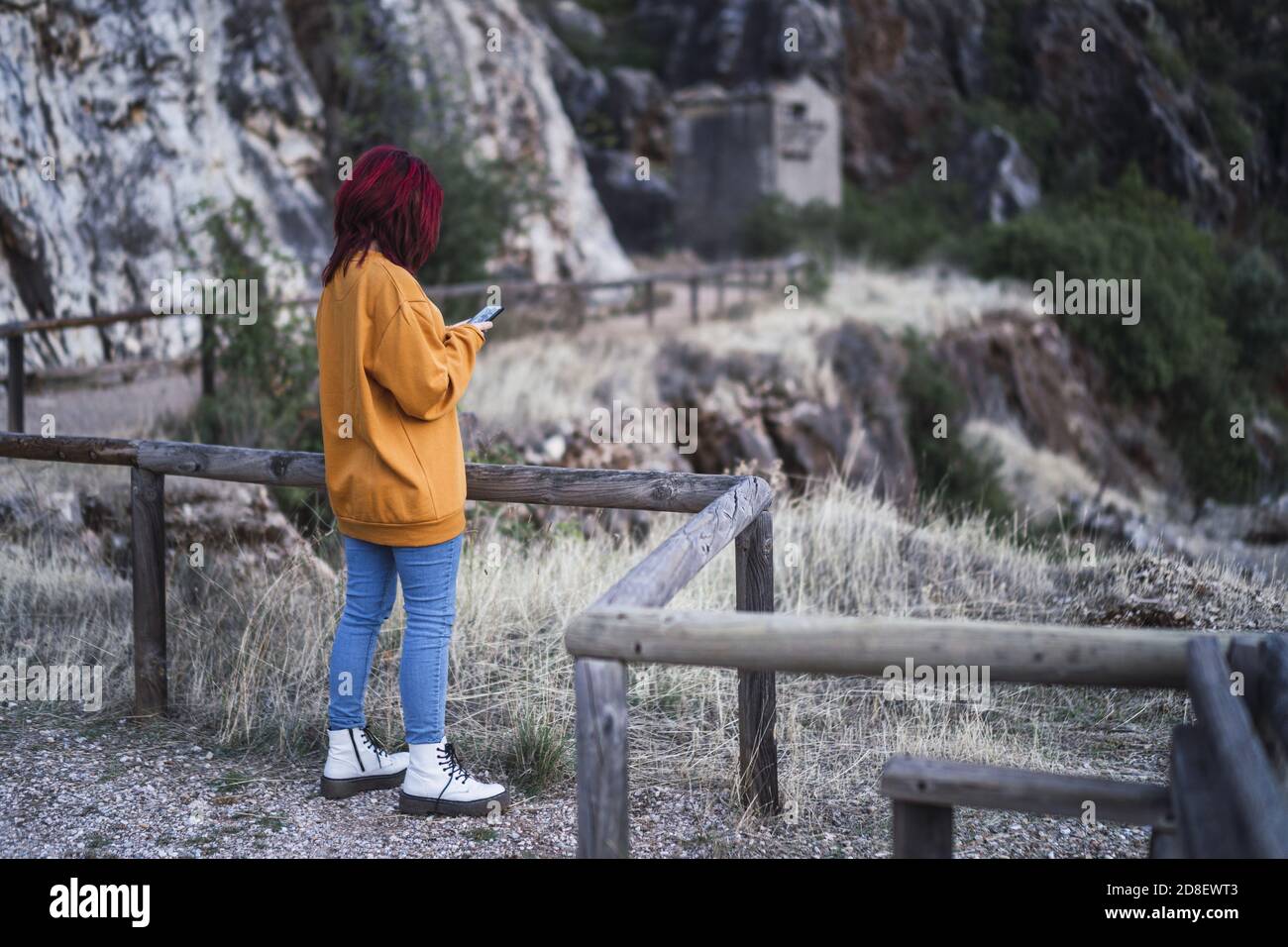 Beautiful red-haired Caucasian female in a yellow sweater using her ...