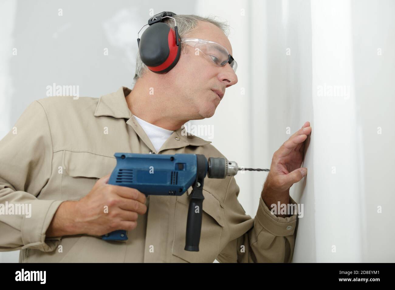 man drilling the wall with drill perforator Stock Photo - Alamy