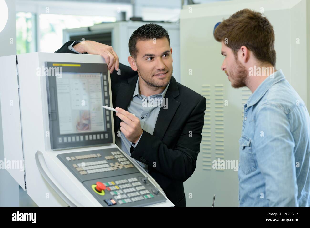 suited man training apprentice technician to use computer monitor Stock ...