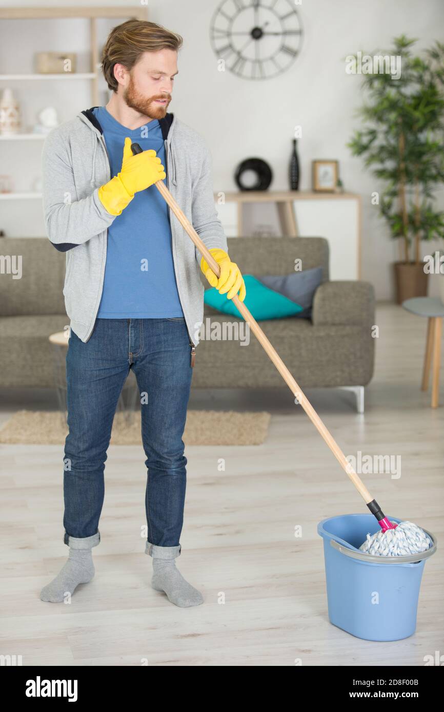 full length of young man mopping floor at home Stock Photo - Alamy