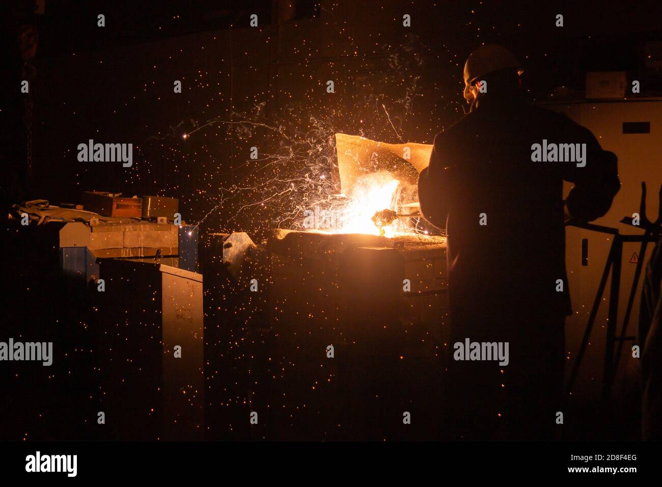 steelworker removing slag from steel furnace with sparks and smoke ...