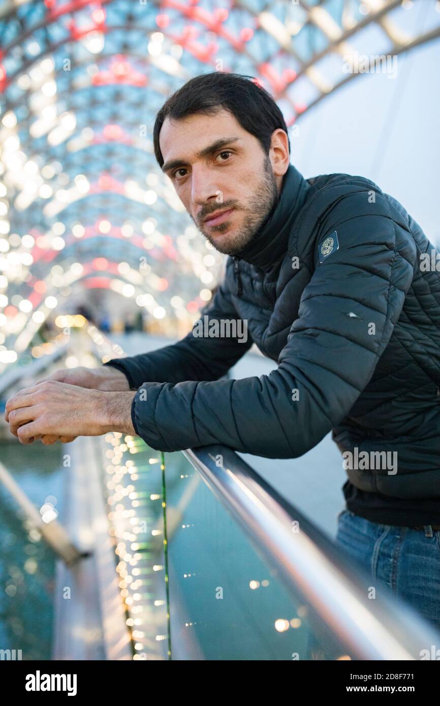 Portrait of a young adult male leaning over the handrail on the Peace ...