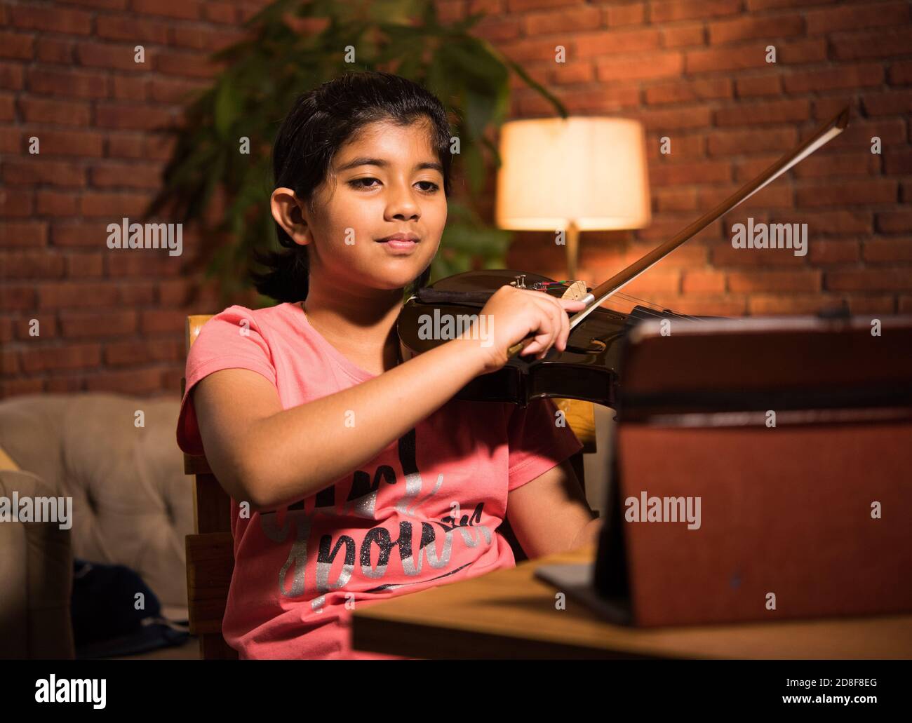 Asian Indian child learning music or musical instrument online using ...