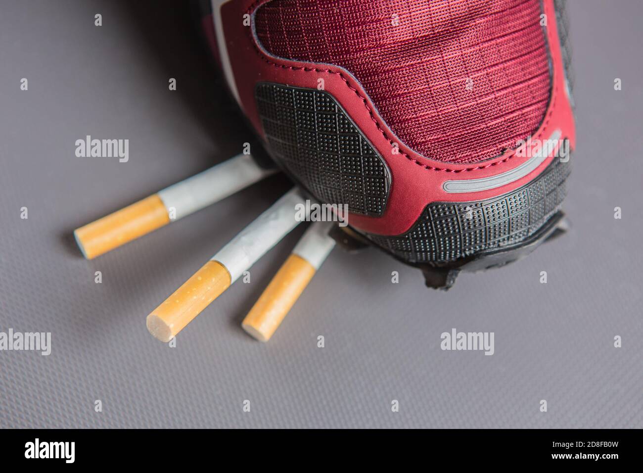 Leg in sneaker treading down cigarettes. Concept of combating smoking ...