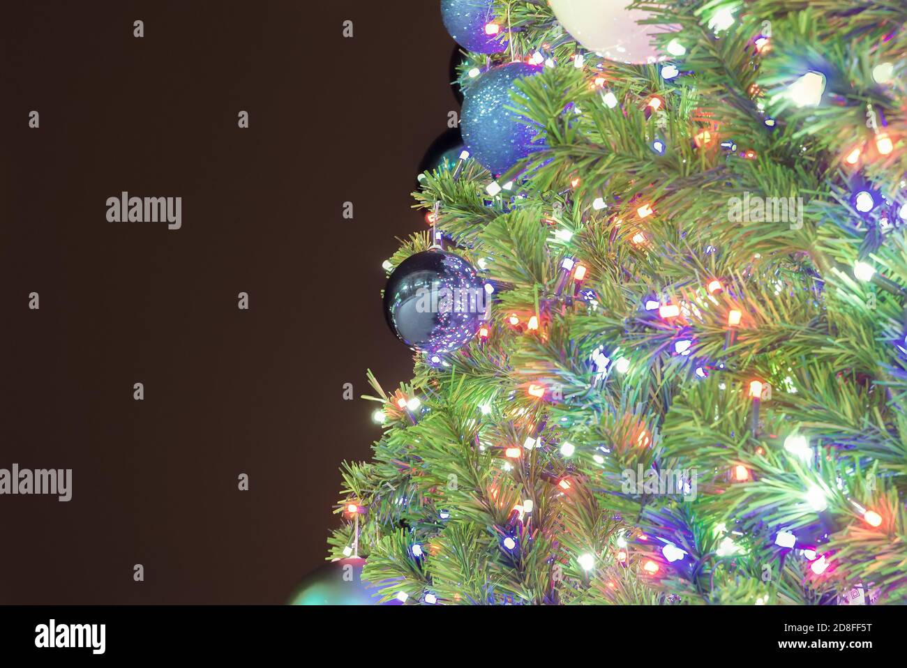 Christmas tree with lights in warm tones on a dark background ...