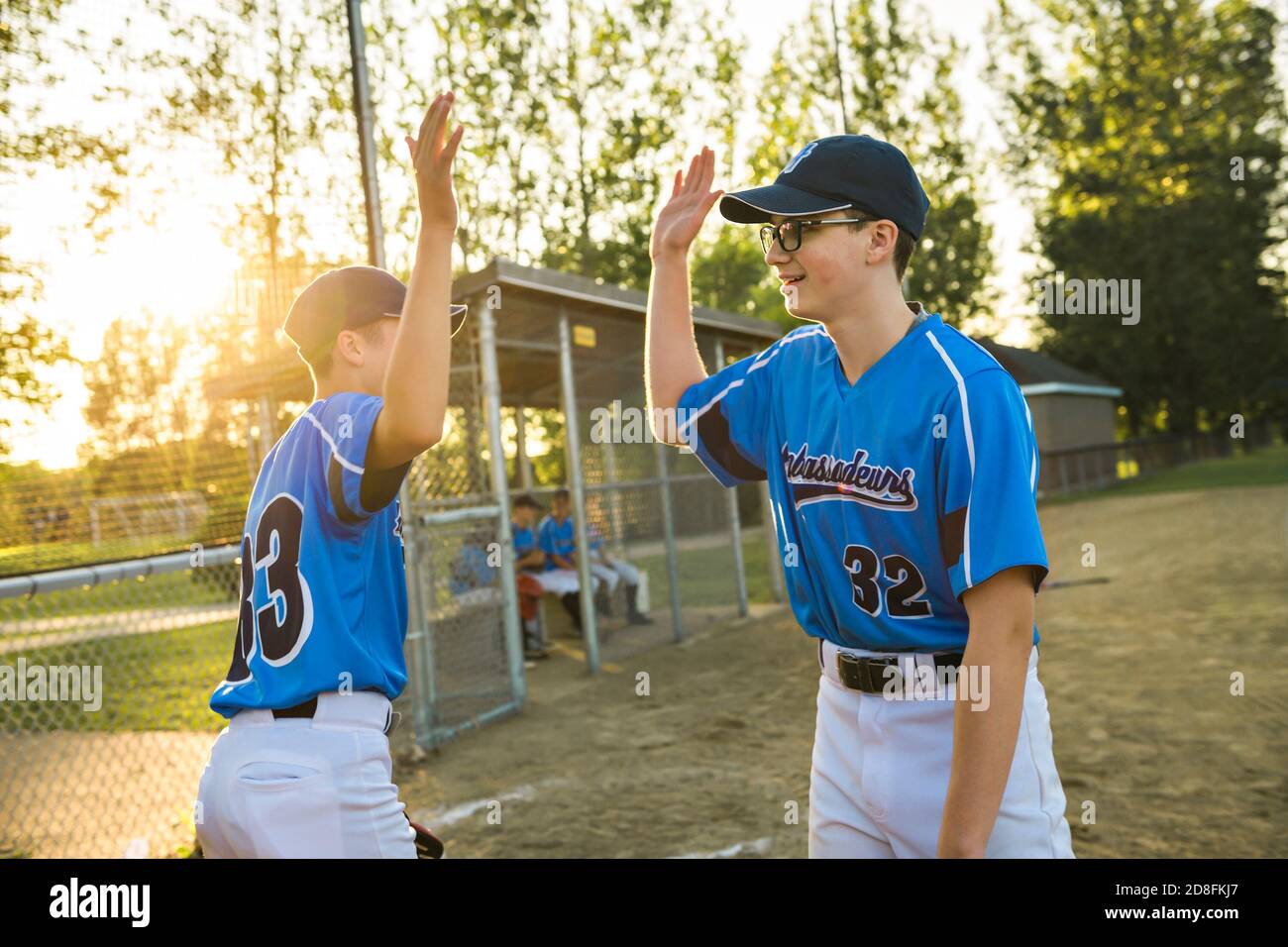 Two childrens baseball players standing together on the playground ...