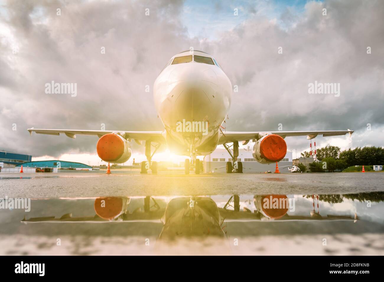 White passenger airplane parked near the hangars with reflection in a ...
